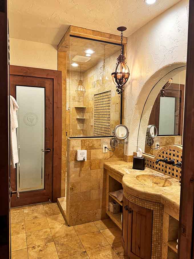 A bathroom that makes you consider the logistics of permanent residency &ndash; travertine tile, vessel sink, and lighting that flatters everyone.