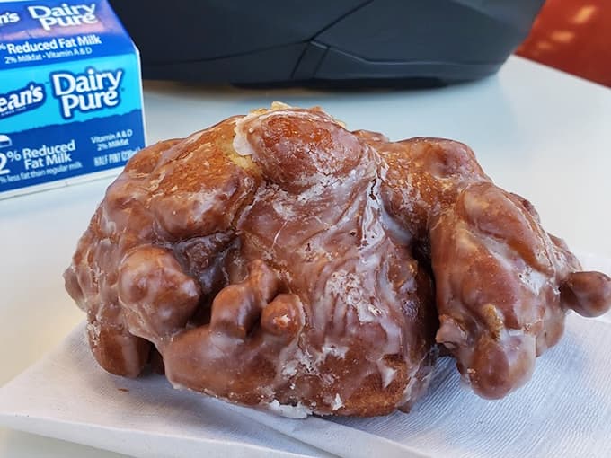 That apple fritter is roughly the size of a small planet and glazed so perfectly it practically glows with deliciousness.
