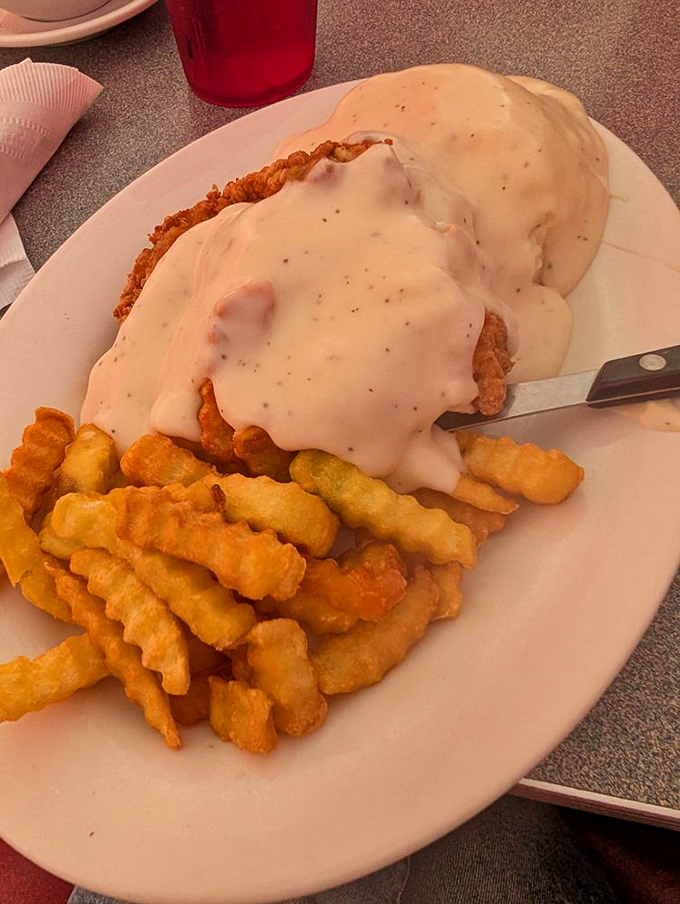 Country fried chicken swimming in creamy gravy alongside golden crinkle fries &ndash; a plate that whispers "nap time" even as you can't stop taking bites.