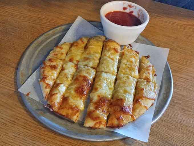 Golden, cheesy breadsticks arrive like edible happiness sticks, perfect for soaking up every last drop of marinara sauce.