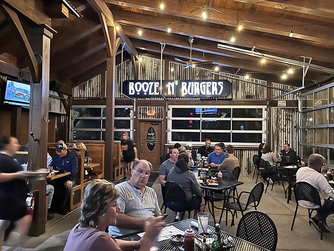 Expanded and Covered Patio: The "Booze N' Burgers" sign presides over a dining area where garage doors blur the line between indoors and out, creating an atmosphere of casual conviviality.