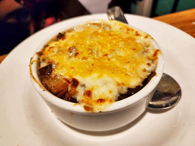 The French onion soup arrives like a bubbling cloud, its golden cheese canopy hiding a savory broth that's worth the inevitable chin dribble.