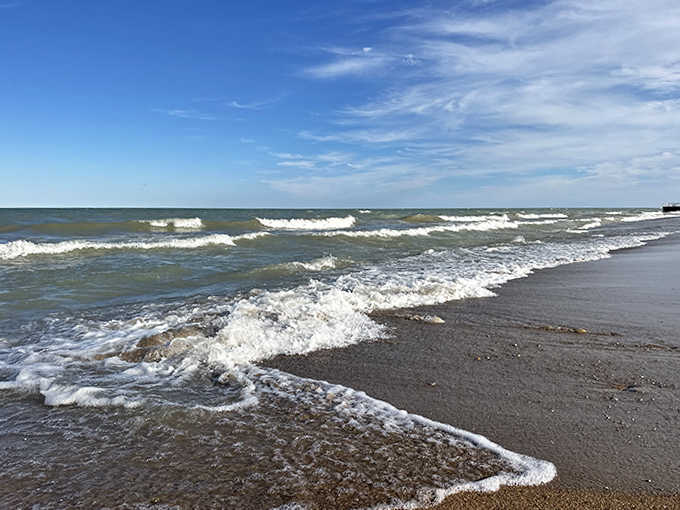 Lake Michigan's gentle waves create a hypnotic rhythm against the shore, nature's own meditation soundtrack for beach-goers seeking peaceful moments.