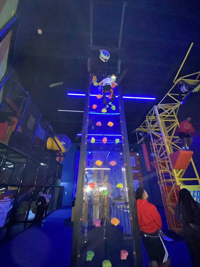 The climbing wall towers overhead like a colorful mountain range, daring visitors to channel their inner Spider-Man with significantly less grace.