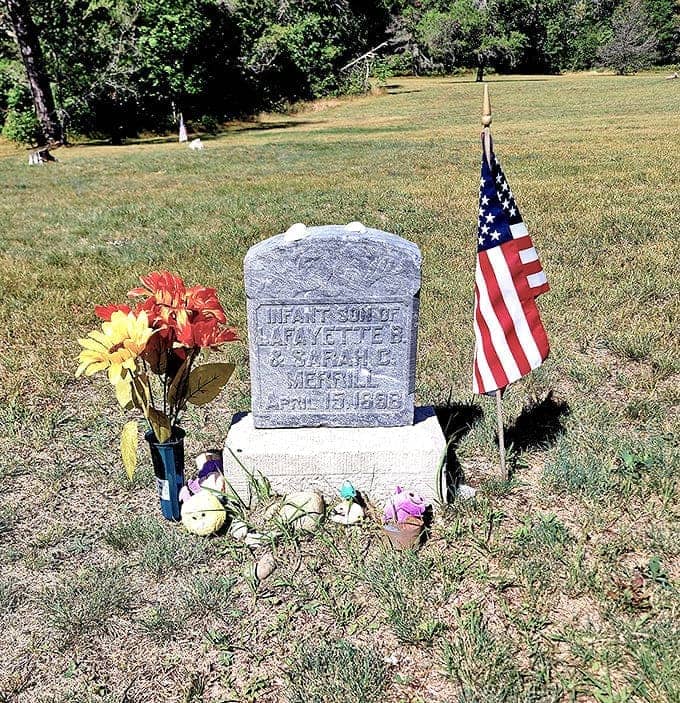 Heartbreaking testimony to frontier hardship &ndash; this infant's grave marker, adorned with flowers and a flag, speaks volumes about Pere Cheney's tragic history.