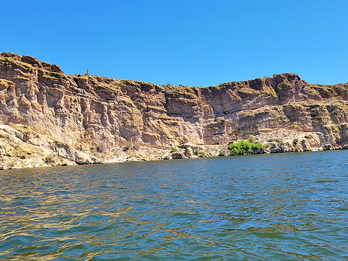 Dramatic cliff walls plunge into calm waters, showcasing millions of years of geological history better than any textbook ever could.