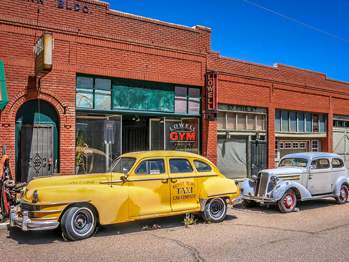 The yellow Lowell Taxi waits eternally for passengers outside the brick Lowell Gym, creating a perfect mid-century vignette.