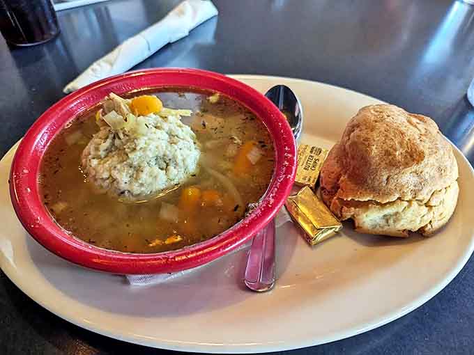 The ultimate comfort duo: a steaming bowl of matzo ball soup paired with a fresh-baked biscuit and a little golden surprise.