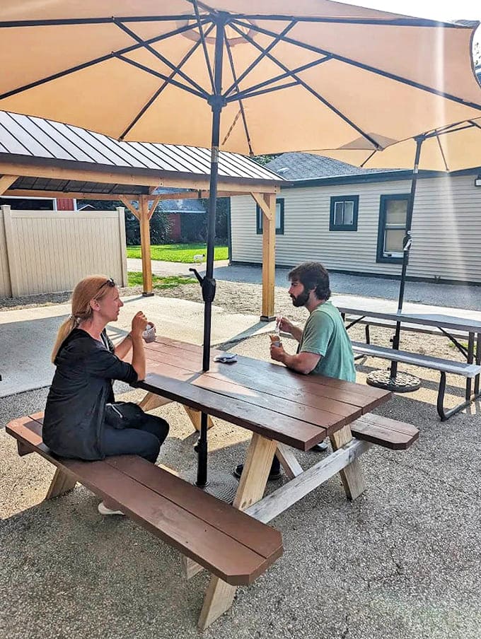 Under the umbrella's shade, these two tackle their frozen treats with the focused determination of people who know they're in for a delicious struggle.