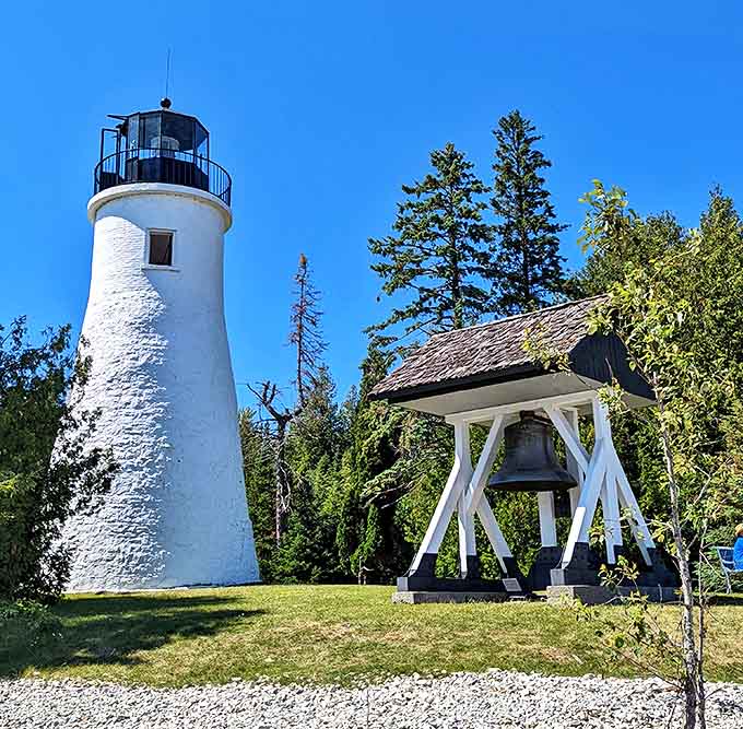 Old Presque Isle Lighthouse gleams white against the blue Michigan sky, a postcard-perfect scene that hasn't changed in generations.