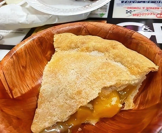 Peach pie that captures summer in a single bite, oozing with golden filling that demands you forget about your dry-clean-only shirt.