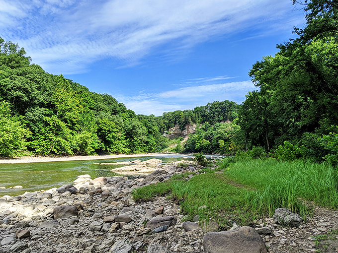 The Vermilion River carves its patient path through verdant banks, a ribbon of blue cutting through Illinois' hidden canyon country.