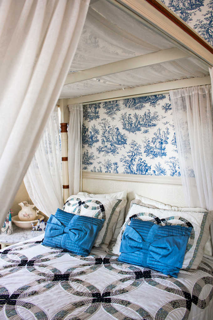 Blue toile wallpaper and a canopy bed create a sleeping space that feels like a Victorian dream.