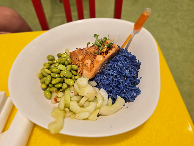 The salmon dish with electric blue rice proves themed restaurants can do healthy options that don't sacrifice Instagram-worthiness for nutrition.