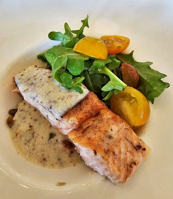 Salmon: Perfectly seared salmon rests on a delicate sauce, accompanied by fresh greens and colorful tomatoes &ndash; a dish that sings when paired with Chardonnay.
