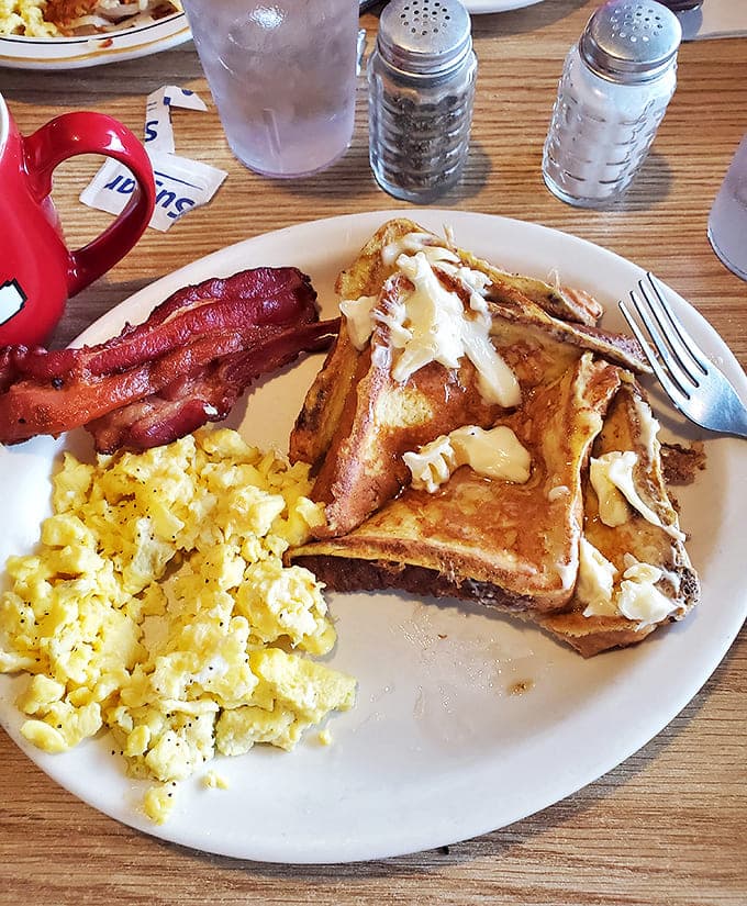 A breakfast that understands balance: fluffy scrambled eggs alongside French toast that's crisp outside, custardy inside, with bacon for good measure.