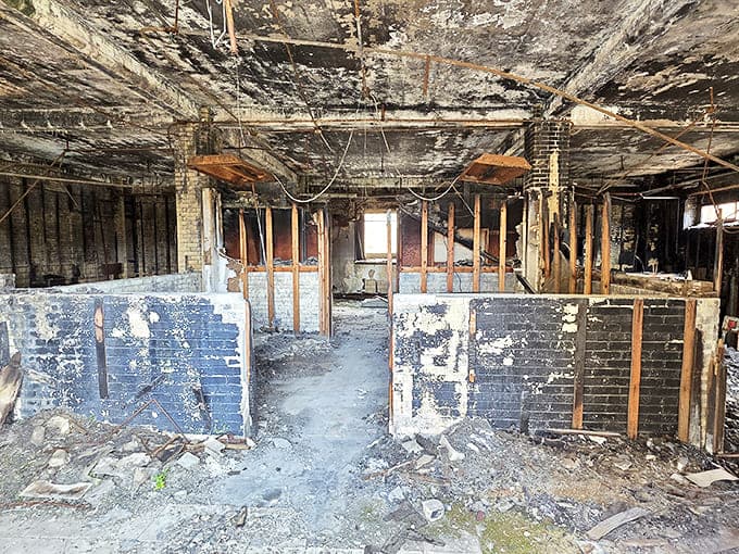 Nature slowly reclaims what man abandoned, as sunlight streams through broken windows illuminating the skeletal remains of prison infrastructure.