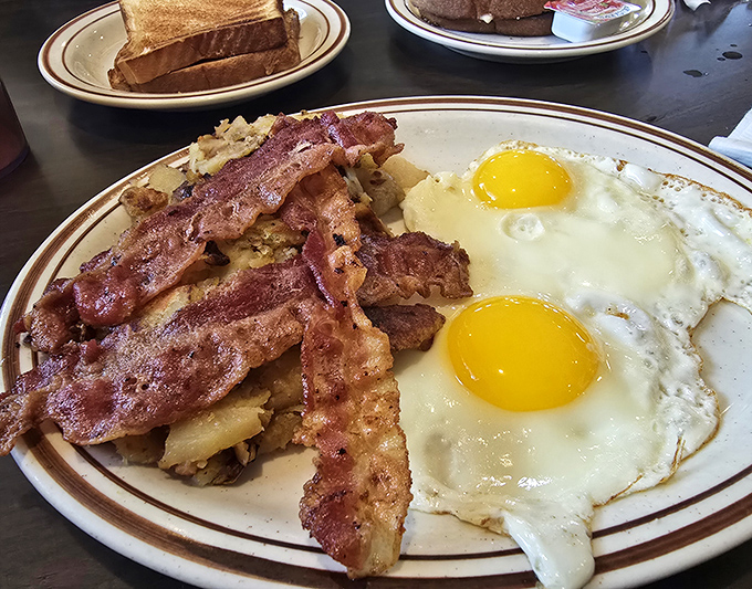 Sunny-side up eggs and crispy bacon atop a mountain of home fries&mdash;proof that sometimes the classics outshine any culinary innovation.
