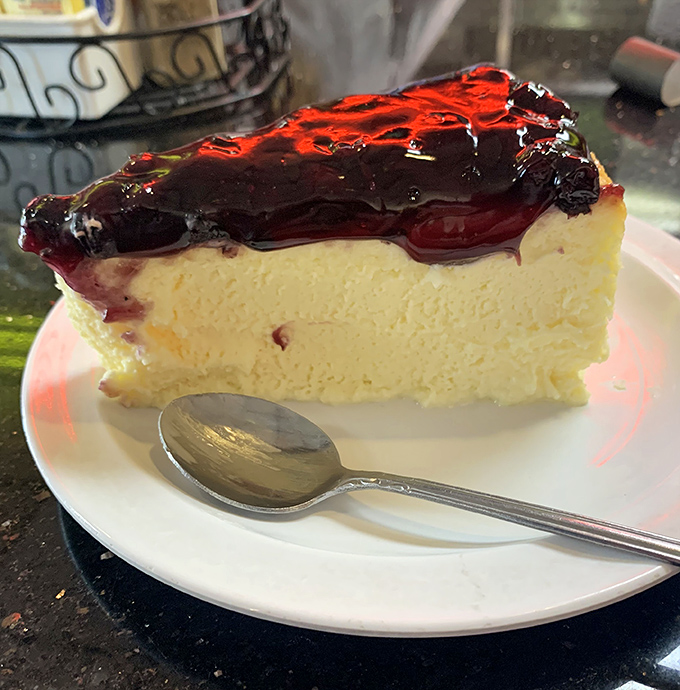 The blueberry cheesecake's glossy topping catches the light like a dessert supermodel. That spoon is about to embark on the journey of its life.