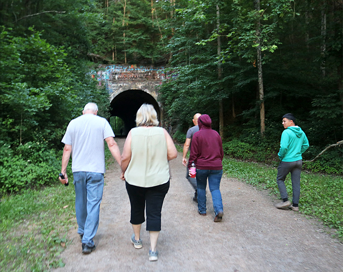 Visitors approach the tunnel's dark mouth, perhaps wondering which ghostly residents might greet them inside.