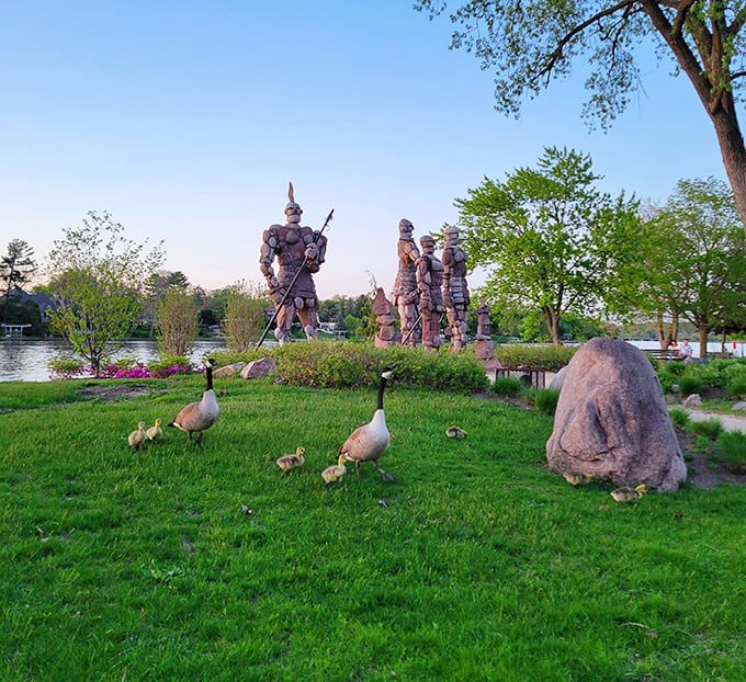 A family of geese waddles past, seemingly unimpressed by the stone giants that have become part of their riverside home.
