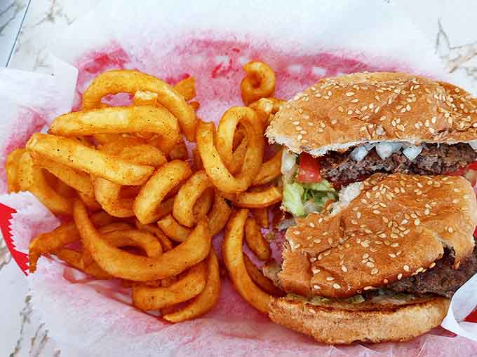 Curly fries that spiral with seasoned perfection alongside a burger that would make fast food chains weep with inadequacy.