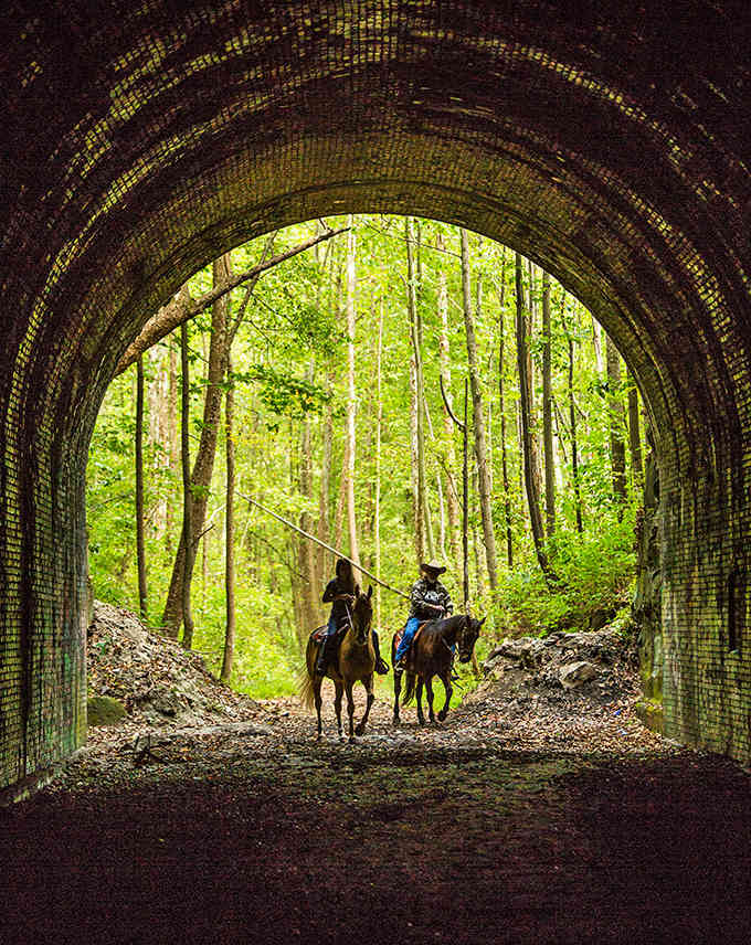 Horseback riders emerge from the tunnel's embrace, creating a scene that could be from either 1890 or today.