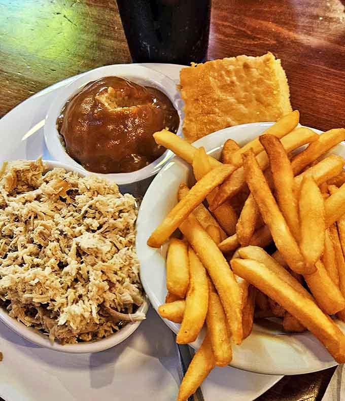 A holy trinity of barbecue perfection: pulled meat, golden fries, and cornbread that walks the sweet-savory tightrope with impressive balance.