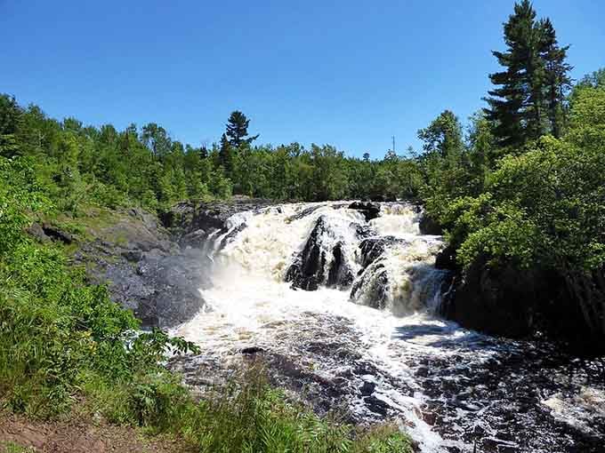 Kawishiwi Falls flows through a narrow channel where water has carved smooth paths through solid rock over countless years of patient work.