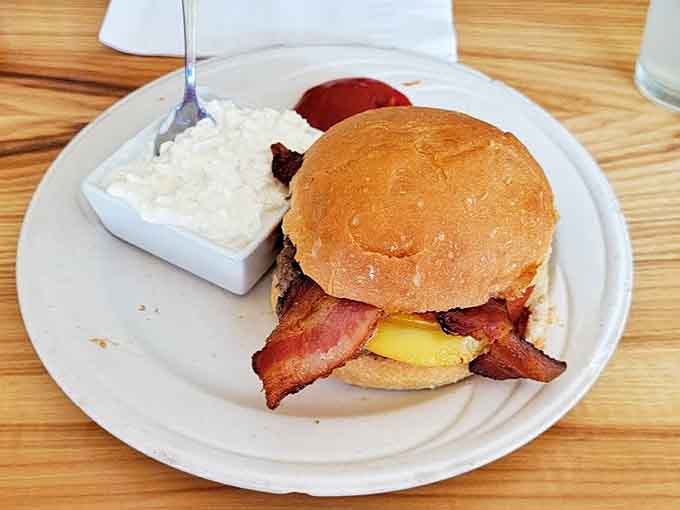 A classic bacon cheeseburger arrives with creamy coleslaw, showcasing the restaurant's ability to elevate simple comfort food to memorable heights.