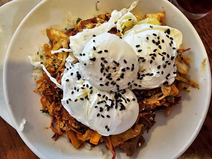 A breakfast bowl that's practically architectural, with perfectly poached eggs perched atop a foundation of savory ingredients and crowned with black sesame seeds.