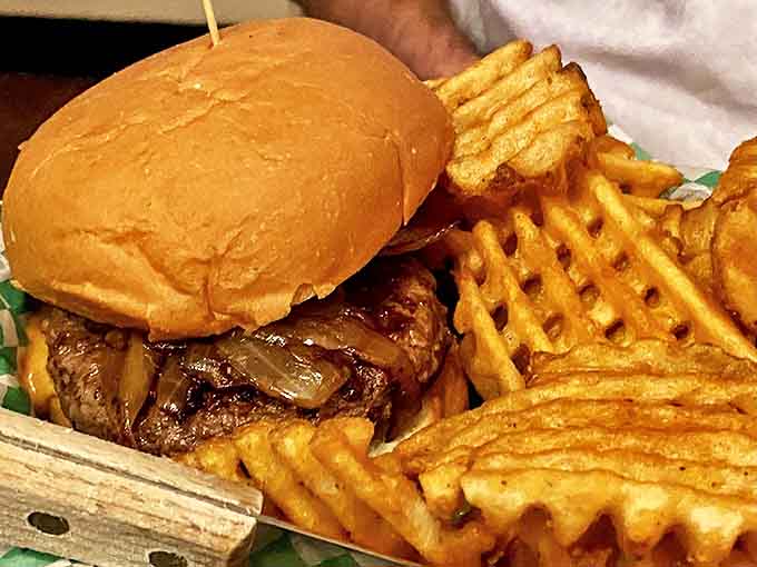 The crispy, geometric precision of waffle fries creates the ideal textural contrast to the juicy, cheese-filled burger.