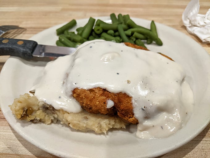 Country fried steak smothered in peppery gravy atop mashed potatoes – comfort food that hugs you from the inside.