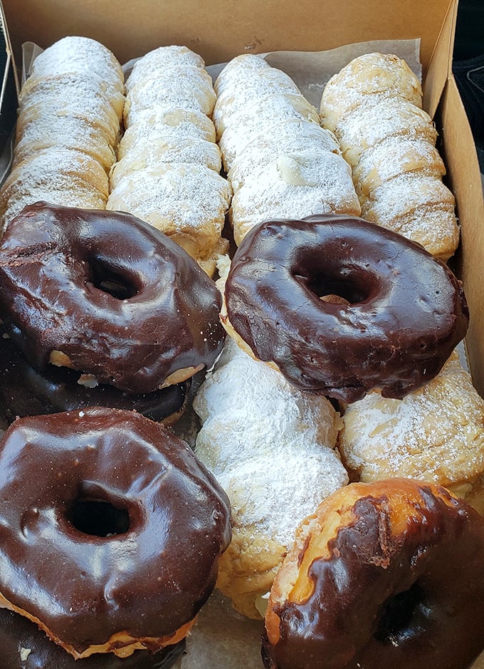 Sweet treasure chest! Powdered delights nestled alongside chocolate-glazed companions – the bakery equivalent of finding buried gold.