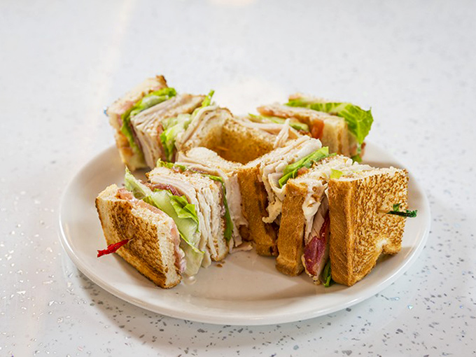 Club Sandwich: Architectural perfection between bread slices &ndash; this club sandwich stands tall and proud, a skyscraper of flavor ready for deconstruction.