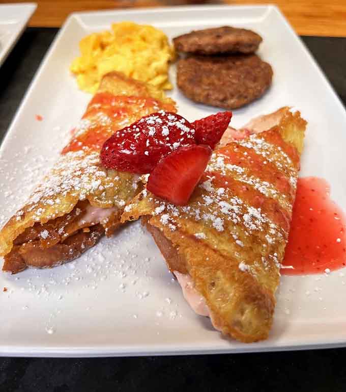 French toast dusted with powdered sugar and paired with sausage links, sweet and savory perfection on one plate.