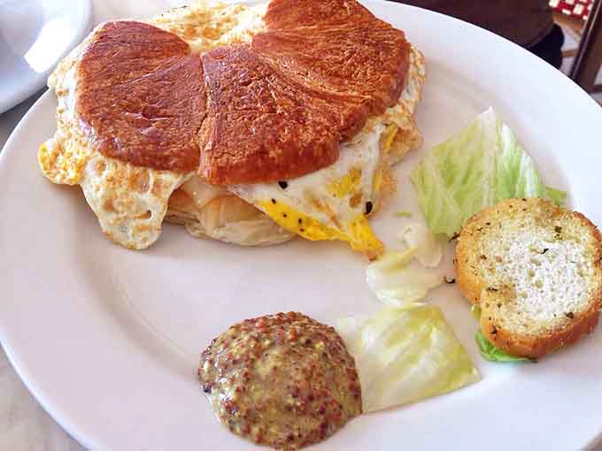 Breakfast elevated &ndash; a perfectly cooked egg nestled in flaky layers with a side of crisp lettuce and zesty mustard.
