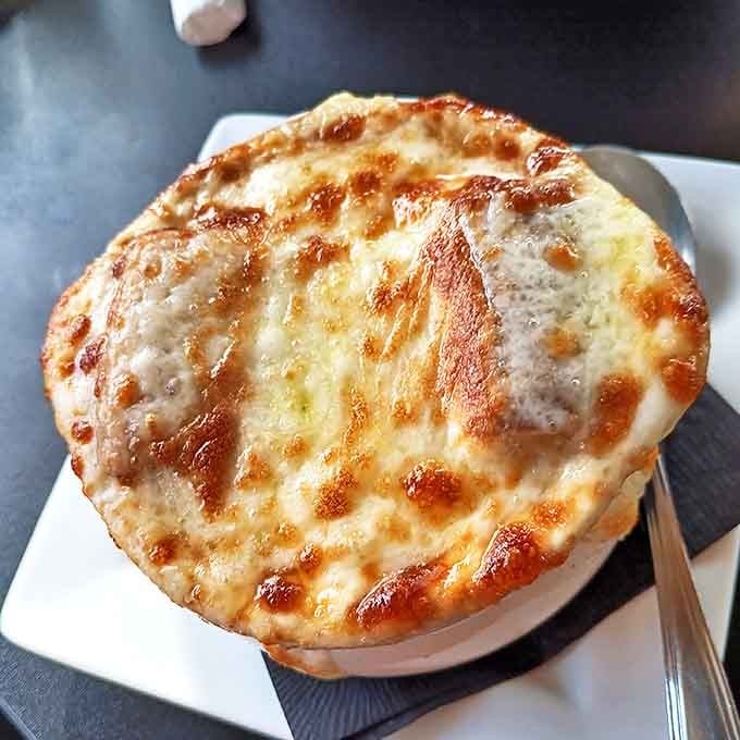French Onion Soup arrives crowned with a glorious dome of bubbling cheese &ndash; break through to discover the savory treasure below.