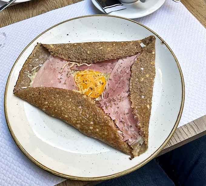 Breakfast gets dressed up in its French finest &ndash; a savory cr&ecirc;pe cradles ham and cheese while a sunny egg adds a pop of color and richness.