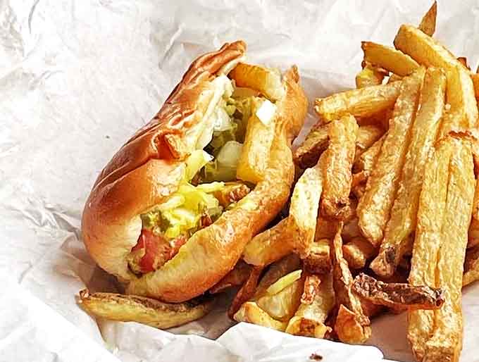 That golden pile of hand-cut fries sitting atop your frankfurter like a crispy crown of pure joy and questionable life choices.