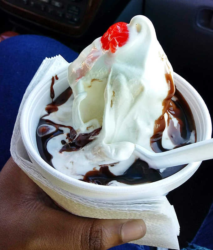 Hot fudge cascades over vanilla ice cream like a chocolate waterfall, creating those perfect ribbons of sweetness that make time stand still.