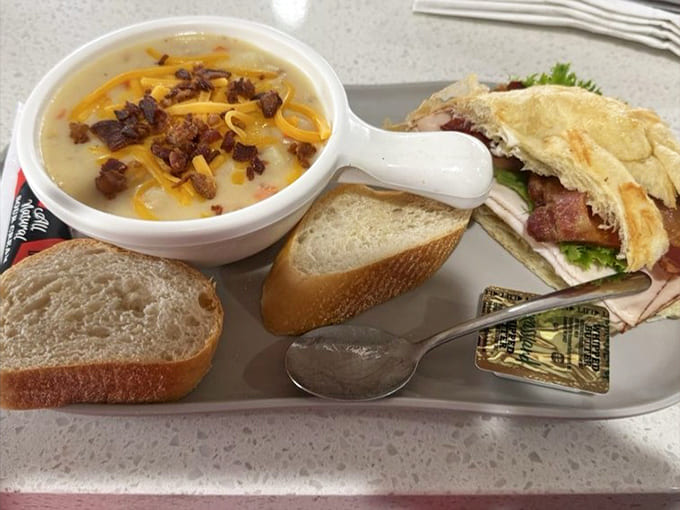 Potato soup loaded with cheese and bacon alongside a stacked sandwich creates the kind of lunch that makes you reconsider all your life choices.