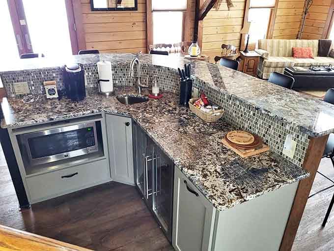 Granite countertops gleam in this thoughtfully designed kitchen where even washing dishes becomes a pleasure with windows framing nature's canvas.