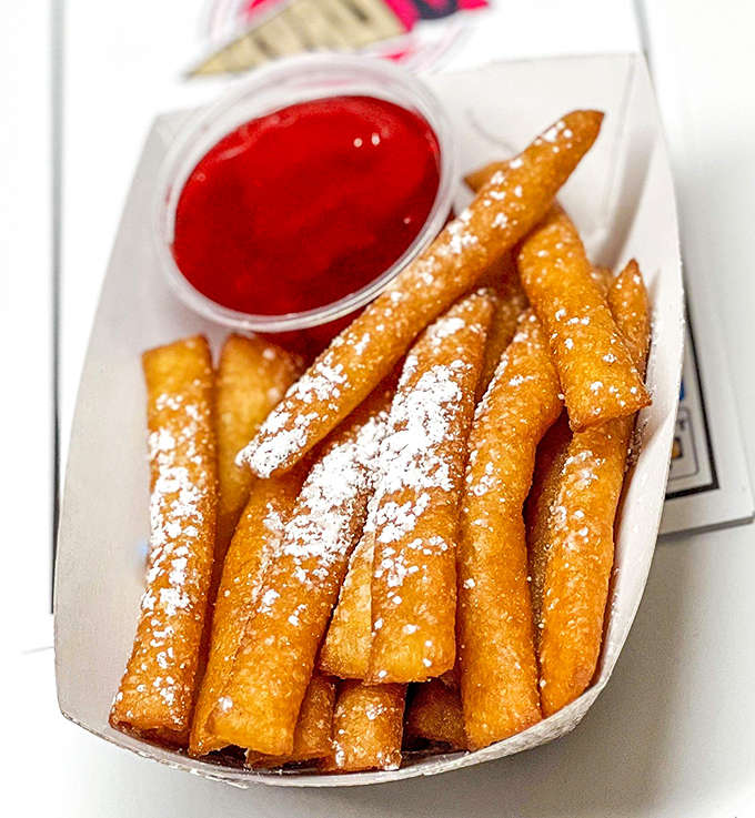 Funnel cake fries dusted with powdered sugar and served with dipping sauce prove that sometimes the best ideas are the simplest ones.