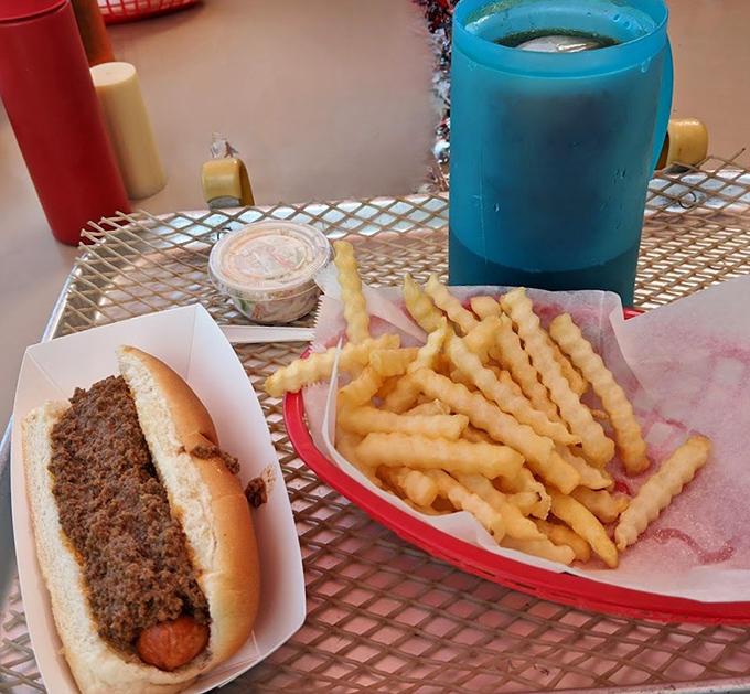 Simple pleasures done right: crinkle-cut fries and a classic coney dog served on a red basket &ndash; comfort food at its finest.