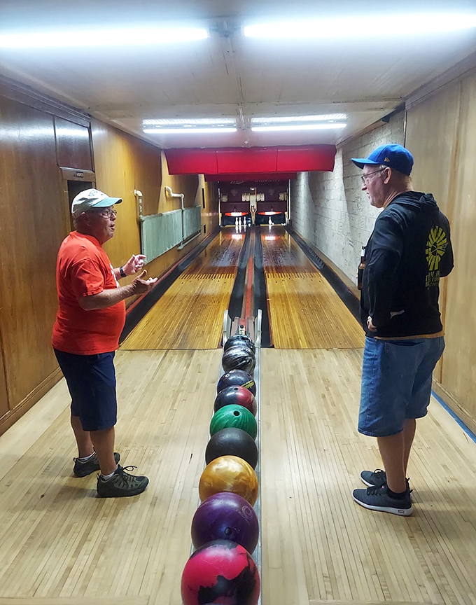 Bowlers prepare for their approach on lanes worn smooth by over a century of footsteps, each depression a testament to history.
