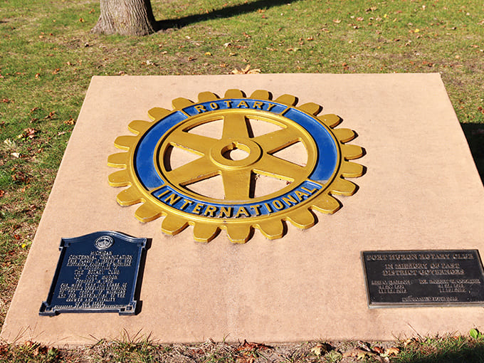 The Rotary International marker stands as a testament to community service, though most visitors are more focused on the beach behind it.