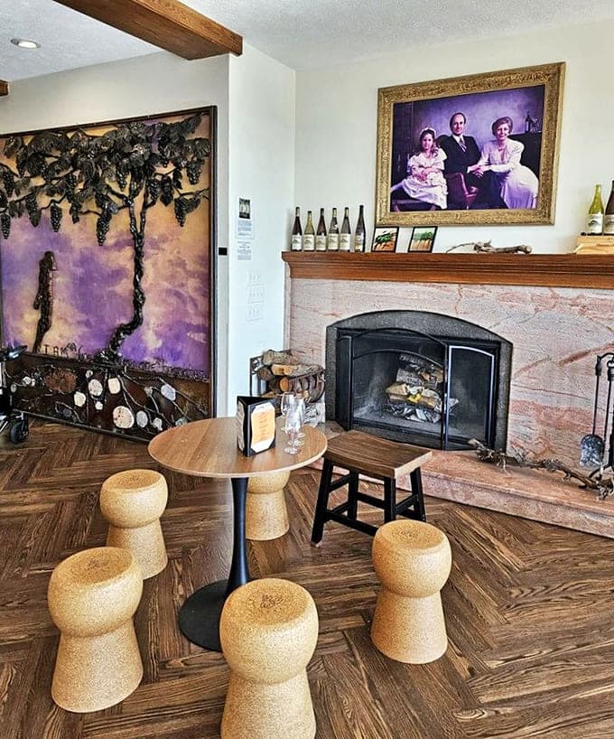 Tasting Room: Warm wood, a crackling fireplace, and cork stools create an intimate tasting space where family portraits watch over memorable wine experiences.