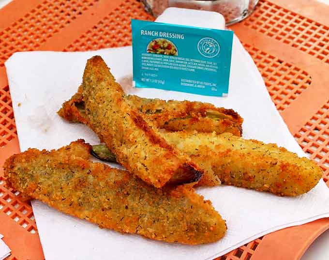 Fried pickles that achieve the perfect balance &ndash; tangy dill interior with a golden, herb-flecked crust that shatters with each bite.