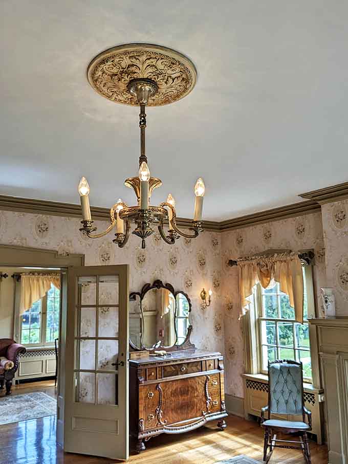 Delicate wallpaper and antique furnishings create a sanctuary where modern guests can dream in vintage splendor. The chandelier's soft glow completes the time-travel illusion.